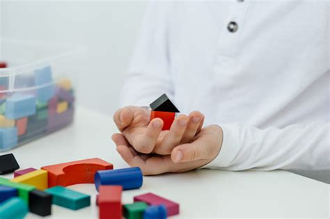 자폐증 진단 및 아동 발달의 개념 한 어린이가 손에 색깔이 있는 나무 조각으로 만든 집을 들고 있다 동작 제어 감정에 대한 스톡