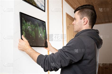把一幅画挂在墙上的人。