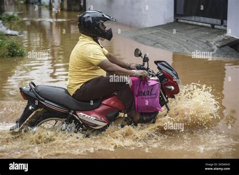 Commuters Make Their Way On A Waterlogged Street After A Heavy Rainfall
