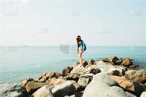 一个背着背包的小女孩赤脚走在海边的巨石上素材 花瓣网