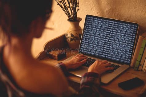 Back View Of Caucasian Female Programmer Sitting At Desk Using Laptop