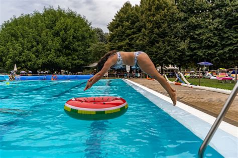 수영복을 입은 젊은 여자가 수영장 가장자리에서 빨간 둥근 구명 부표로 장난스럽게 다이빙 25 29세에 대한 스톡 사진 및 기타