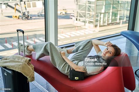 공항 여행 라이프 스타일 출발 전에 비행기를 기다리는 동안 수하물 트롤리 가방 여권 스마트 폰 및 티켓과 함께 터미널 홀에 앉아