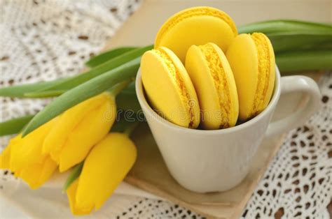 Желтое французское Macaron и желтые тюльпаны на старой книге Стоковое