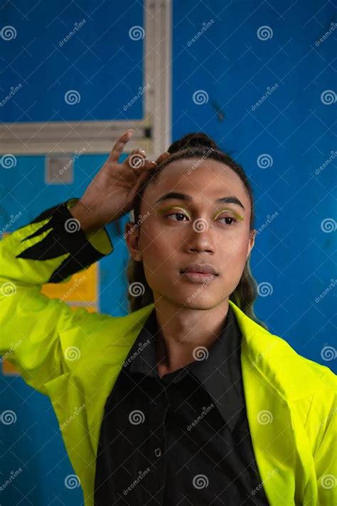 An Asian Man With Long Curly Hair Is Posing In Front Of A Blue Wardrobe