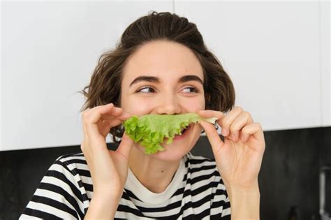 Retrato De Uma Mulher Sorridente Segurando Uma Planta Contra A Parede