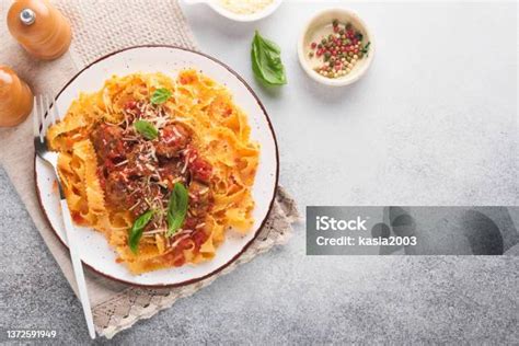 토마토 소스에 미트볼을 곁들인 타글리아텔 파스타와 백리향을 연한 회색 슬레이트 돌 또는 콘크리트 배경에 소스로 넣습니다 전통 이탈리아 요리와 요리 복사 공간이 있는 상단