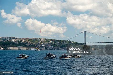 밝은 날 터키 이스탄불의 보스포러스 해협 다리 아래를 지나는 큰 배와 함께 보스포러스 해협의 어선과 터키 국기를 배경으로 한 어선 0명에 대한 스톡 사진 및 기타 이미지