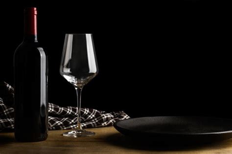 Premium Photo A Bottle Of Red Wine And A Glass On A Wooden Table In A