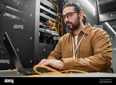 Engineer Wearing Eyeglasses And Typing On Laptop In Data Center Stock