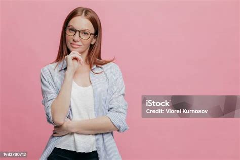 매력적인 젊은 여자의 실내 촬영 분할 넘어 손을 유지 카메라에서 심각 하 게 보이는 우아한 셔츠와 바지를 입고 귀하의 광고에 대 한 복사 공간 핑크 스튜디오 벽에 모델 30