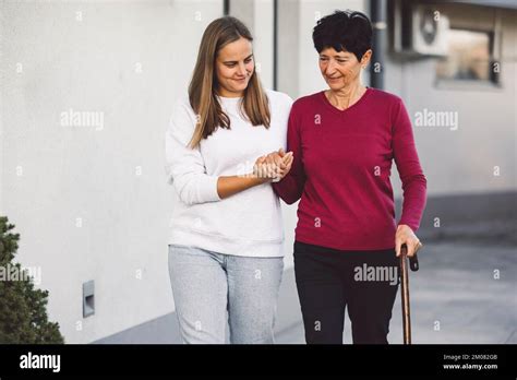 Young Woman Working As A Home Nurse Taking Care Of A Senior Lady Who Is Having Trouble Walking
