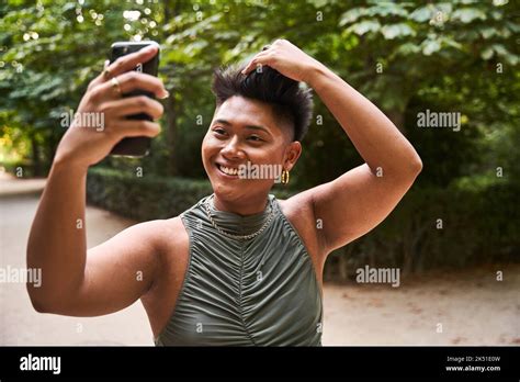 Happy Filipino Transgender Woman Smiling And Touching Short Hair While