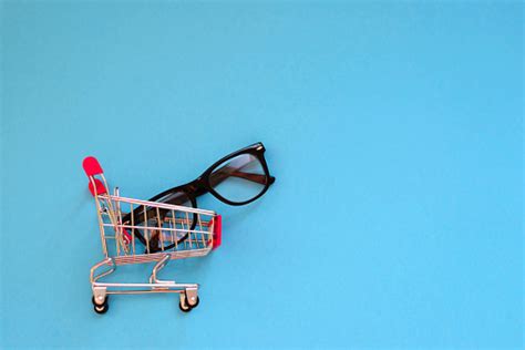 파란색 배경의 작은 장바구니에 검은 색 플라스틱 프레임에 있는 어린 아이들을 위한 어린이 용 안경 복사 공간 어린이 용 안경용 특수 파손 방지 프레임 0명에 대한 스톡 사진