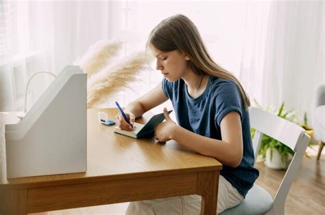 Premium Photo A Smart Teenage Schoolgirl Makes Notes In A Notebook