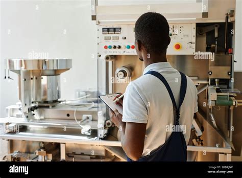 Back View Of African American Factory Worker Holding Clipboard While