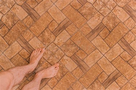 Barefoot Men S Feet Stand On A Brown Floor Tile With A Stone Abstract