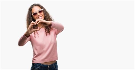 美しい若いヒスパニック系女性のサングラス ハート記号と手で形を示す愛の笑顔しますロマンチックな概念 1人のストックフォトや画像を多数ご用意