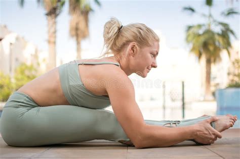 Side View Portrait Of Young Fitness Woman Stretching Legs Outdoors