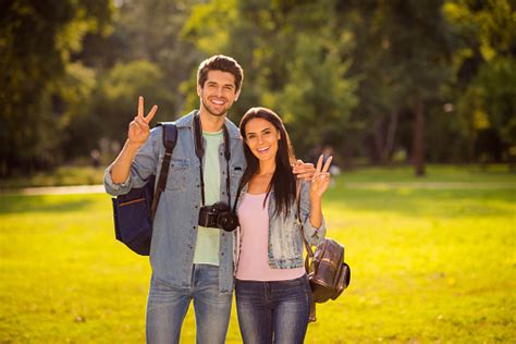 그녀 그 그 그 좋은 매력적인 매력적인 쾌활한 쾌활한 결혼 배우자 여행자 관광객 관광객 지출 꿀 달 에 신선한 공기 보여주는 V기호 에 녹색 나무 숲 빛나는 날 2명에 대한