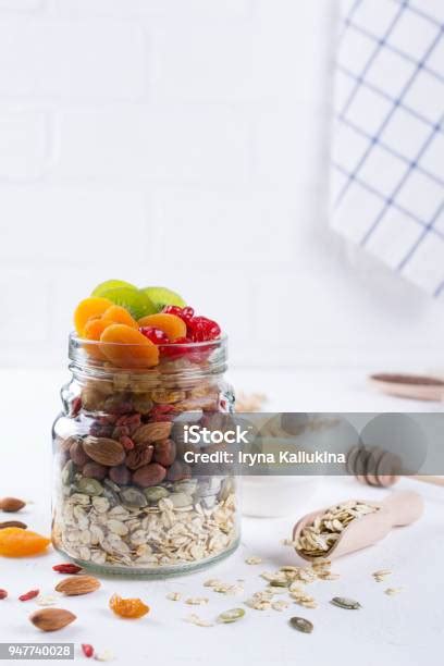 흰색 배경에서 그 라 놀라를 요리 재료로 유리 항아리 귀리 플레이크 꿀 견과류 말린 과일 및 씨 건강 한 답 0명에 대한 스톡
