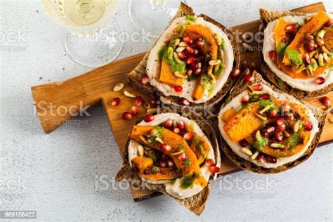 후 머 스와 Arugula Pesto와 서빙 보드에 구운된 호박 빵 간식 석류와 잣의 씨앗입니다 건강에 좋은 음식 0명에 대한