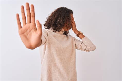 고립된 흰색 배경 위에 서서 손으로 눈을 가리고 슬프고 두려움표현으로 제스처를 멈추고 있는 젊은 브라질 여성 부끄럽고 부정적인