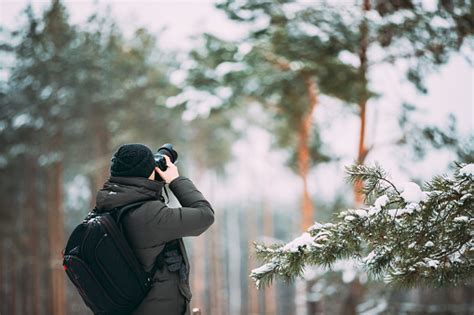 겨울 눈 덮인 숲에서 사진 카메라로 사진을 찍는 젊은 남자 배낭 활동적인 취미 눈 덮인 파인 우드 숲에서 산책 하는 하이커 20