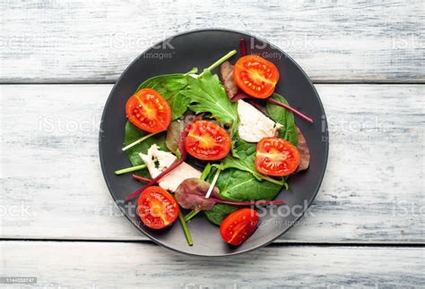 나무 배경에 어두운 접시에 샐러드에 대 한 Arugula 양상추 시금치 토마토와 치킨 필 레의 신선한 잎을 섞는다 메뉴판에 대한