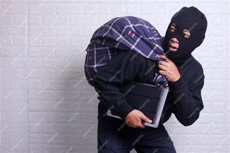 Premium Photo Thief Male Dressed In A Black Hoodie With A Disguised Face Runs Away After