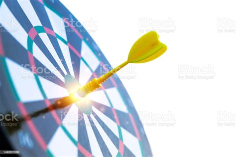 close up yellow dart arrow hitting target center dartboard on sunset