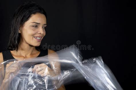 Portrait Of Woman With Clear Plastic In Front Of Her Body Against Black