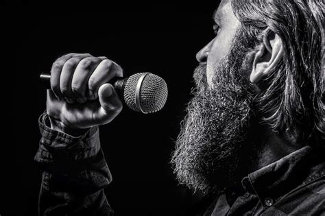 Premium Photo Man With A Beard Holding A Microphone And Singing