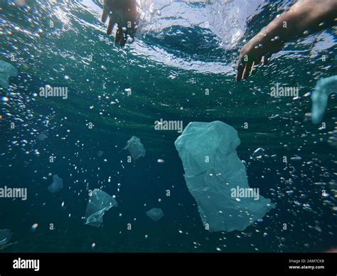 A Man Swimming Among Toxic Plastic Wastes Floating In The Ocean Stock