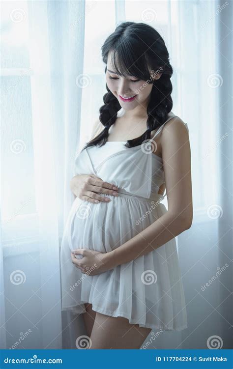 Young Pregnant Asian Woman Holds Her Hands On Her Swollen Belly Love