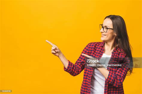 갈색 머리의 초상화 아름 다운 매력적인 아름 다운 젊은 여자 Logn 머리를 가진 유리에 Yelliow 배경 위에 고립 된 고립 된 손가락으로 측면을 가리키는 표시 복사