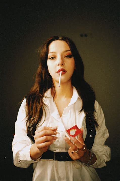 검은색 배경 긴 머리 담배 담배를 피우는 머리카락에 손을 대다 빨간 옷 수직 쐈어 얼굴 여성 초상화 패션 사진 포즈를 취하는에 관한 무료 스톡 사진