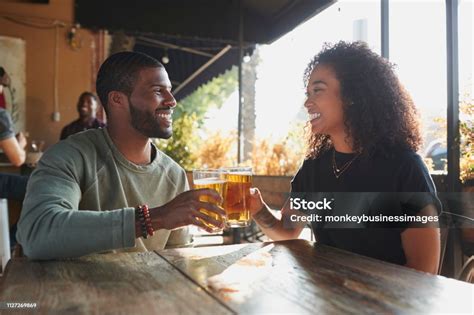 젊은 커플 게임을 하기 전에 음료를 즐기는 스포츠 바에서 회의 커플에 대한 스톡 사진 및 기타 이미지 커플 마시기