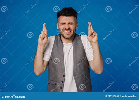 Young White Unshaven Man Squeezing His Eyes And Holding Fingers Crossed