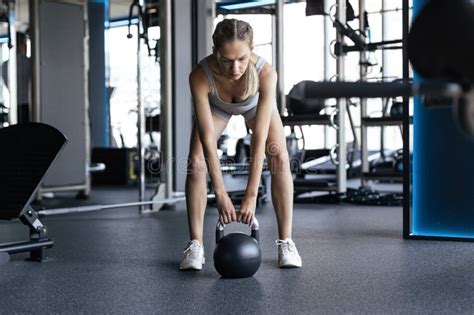 Sporty Woman In A Grey Top And Shorts Doing Sit Ups With A Weight