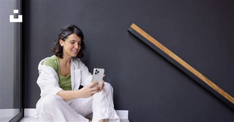 A Woman Sitting On The Floor Using A Cell Phone Photo Free Woman