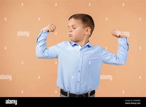 Der Kleine Junge Zeigt Seine Bizeps Auf Beigefarbenem Hintergrund Das