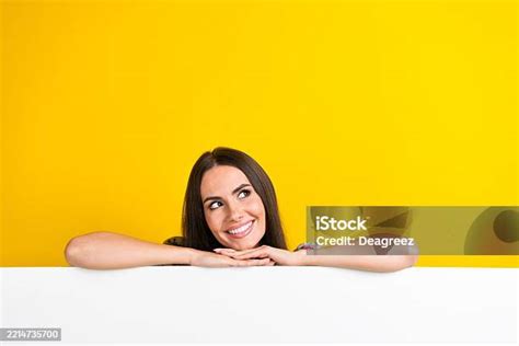 이빨이 빛나는 여자의 초상화는 세련된 옷을 입고 벽에 손을 잡아 꿈꾸는 듯한 빈 공간을 노란색 배경에 고립 시켰습니다 갈색