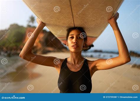 African American Woman Standing With Surfboard On Head On Ocean Beach
