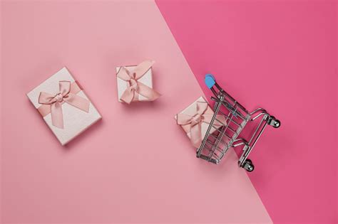 분홍색 파스텔 배경에 활이있는 쇼핑 트롤리와 선물 상자 크리스마스 생일 또는 결혼식을위한 구성 개념에 대한 스톡 사진 및 기타