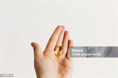 흰색 벽 배경에 오메가 3 캡슐을 손에 들고 있습니다 비타민의 아침 복용량 알약에 생선 기름 식이 보조 제 건강 지원 및 치료