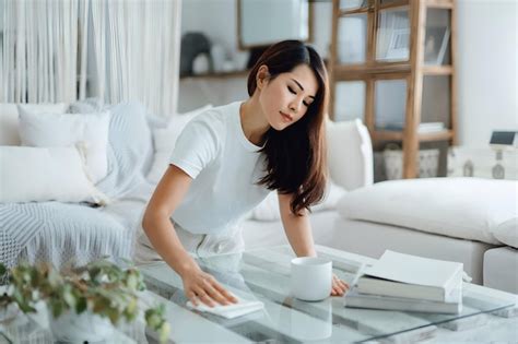 Premium Photo Young Asian Woman Tidying Up The Living Room And Wiping The Coffee Table Surface
