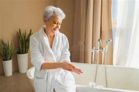 Mature Adult Old Woman Applying Moisturizing Body Lotion On Hands