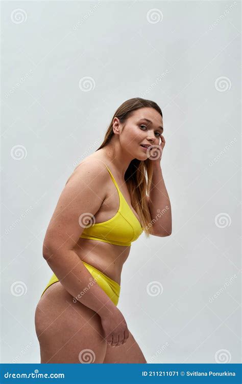 Side View of Adorable Curvy Female Model Wearing Yellow Underwear Looking at Camera while Posing ...