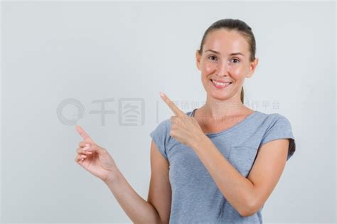 穿着灰色 T 恤的年轻女性指着旁边，看上去很高兴。正视图。动物植物免费下载格式626像素编号53615285 千图网